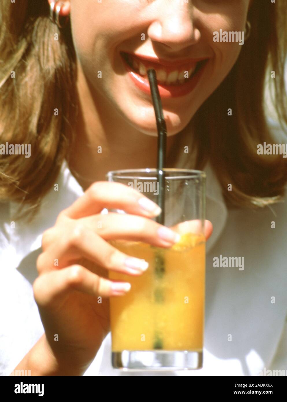 Drinking orange juice. Young woman drinking orange juice through a ...