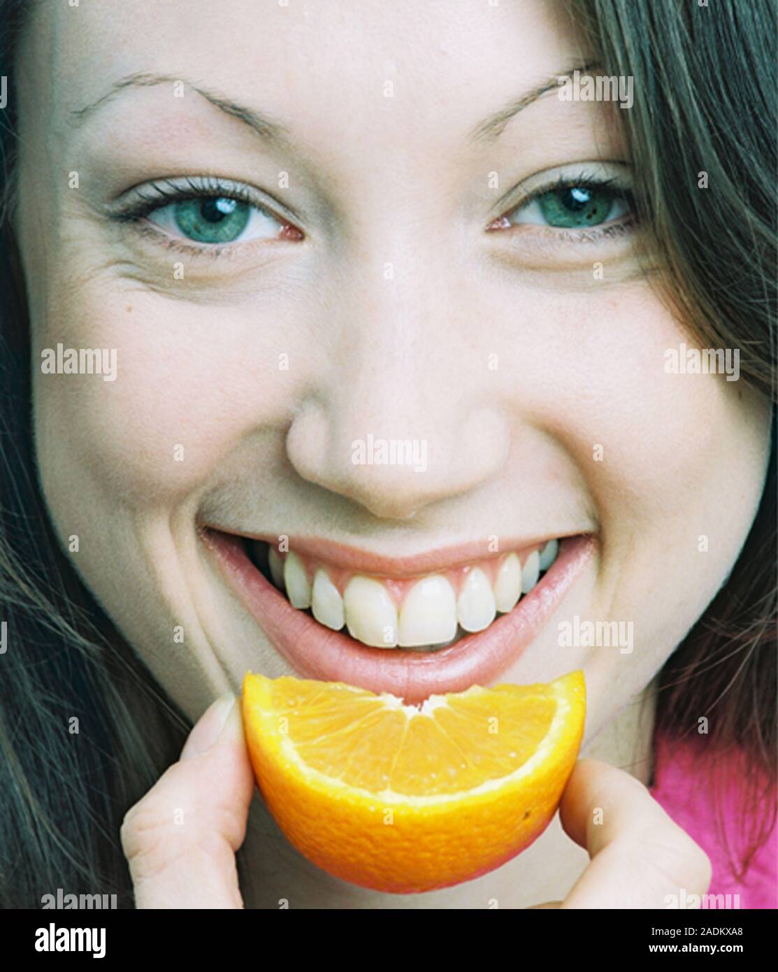 Eating an orange slice. Woman eating a slice of orange (Citrus sinensis ...