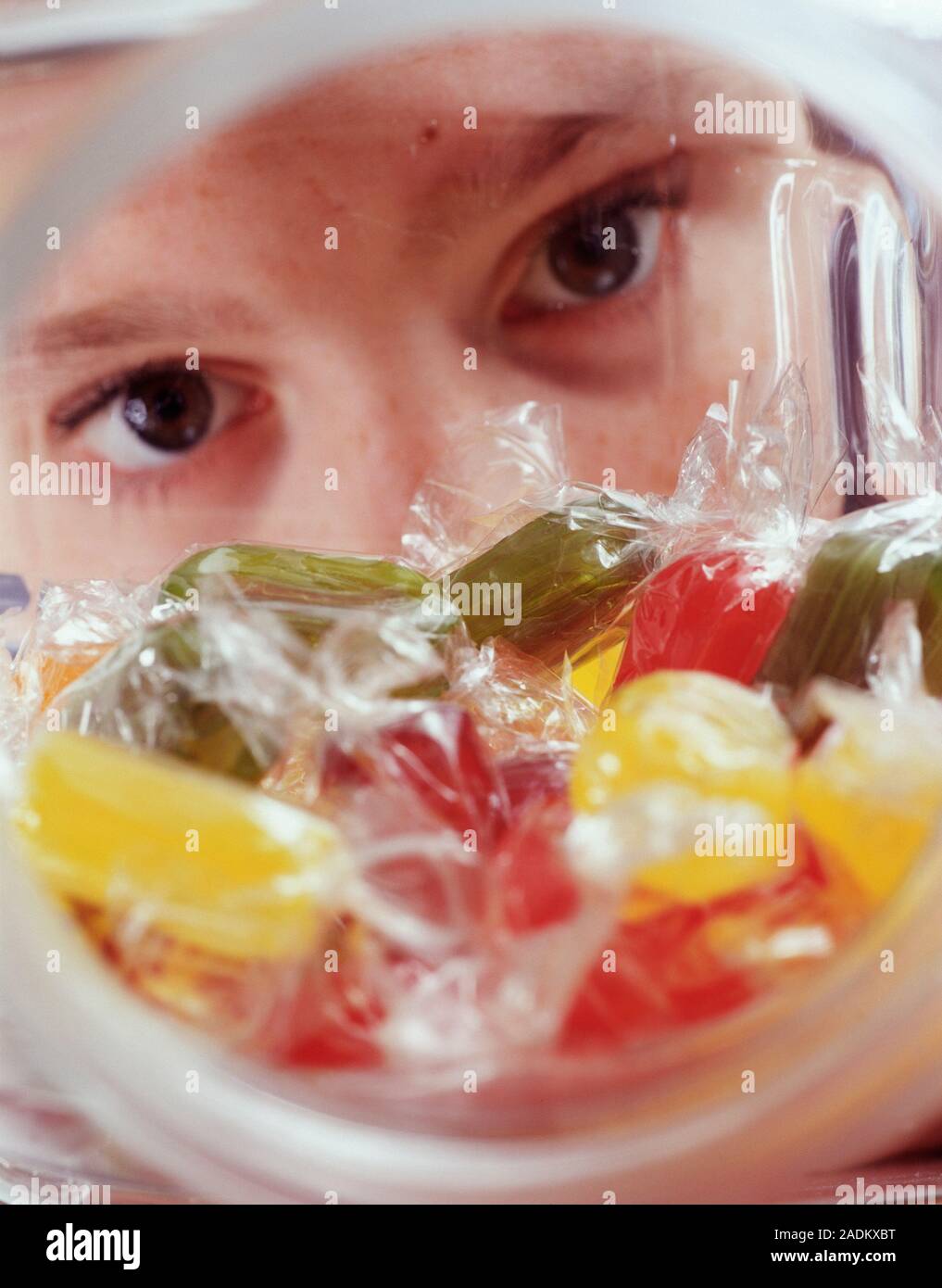 Eating sweets. Boy peering into a jar of sweets. Sweets contain high ...