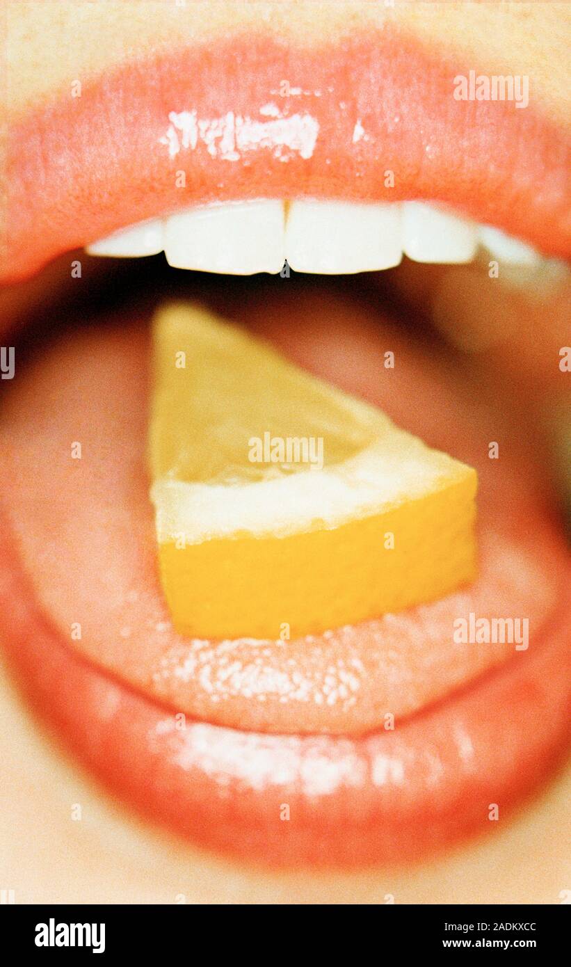 Slice of lemon. Woman with a slice of lemon (Citrus limon) on her ...