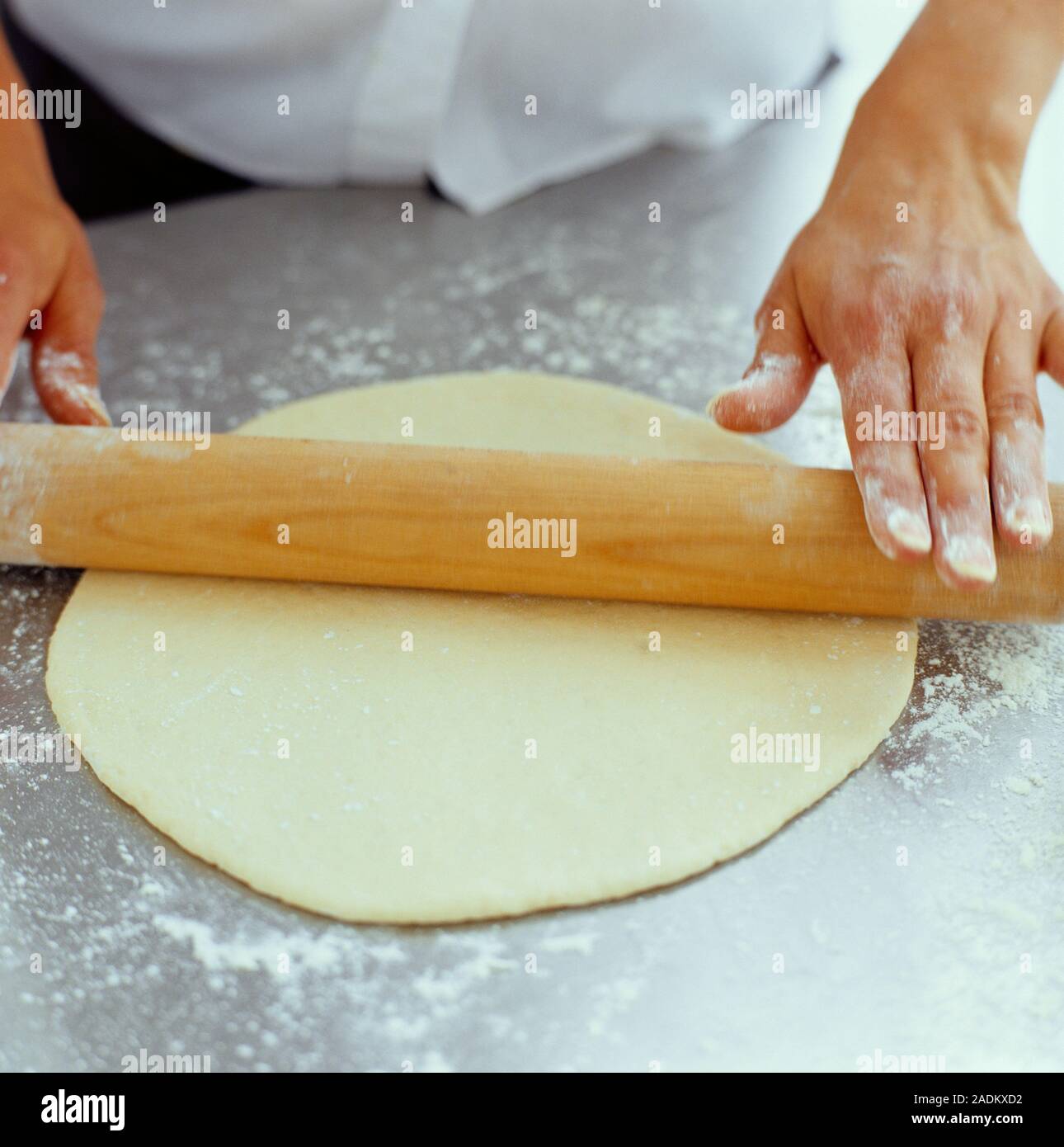Rolling dough. Hands rolling dough using a rolling pin. Dough is a ...