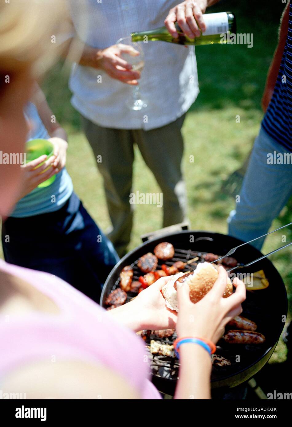 MODEL RELEASED. Barbecue food. Girl helping herself to food from a ...