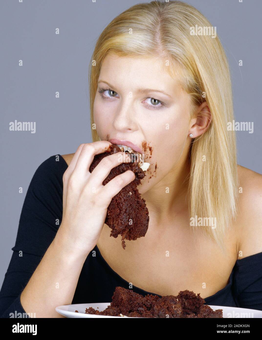 Woman eating cake. Woman stuffing a slice of chocolate cake into her ...