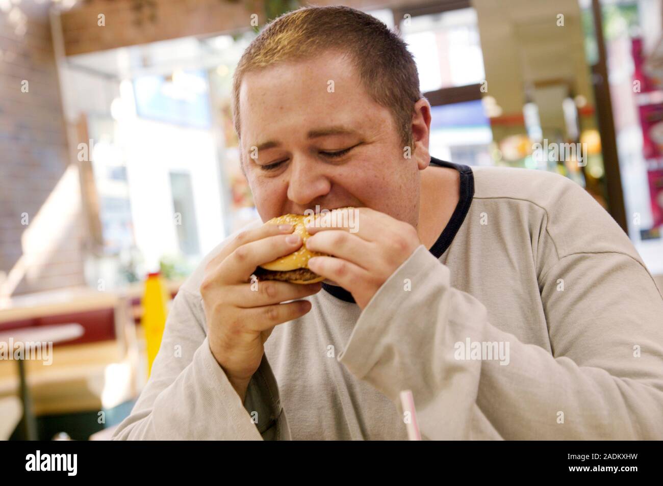 Obese man eating a burger in a McDonald's restaurant Stock Photo - Alamy