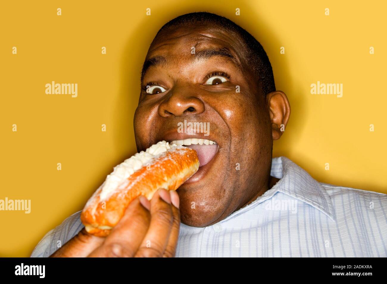 Man eating a creamy finger doughnut Stock Photo - Alamy