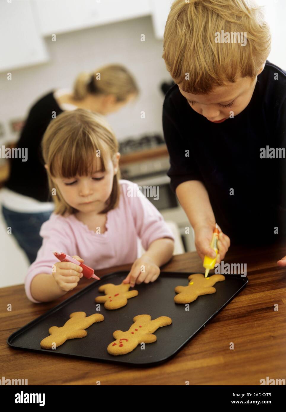 MODEL RELEASED. Making biscuits. Two three year old children decorating ...
