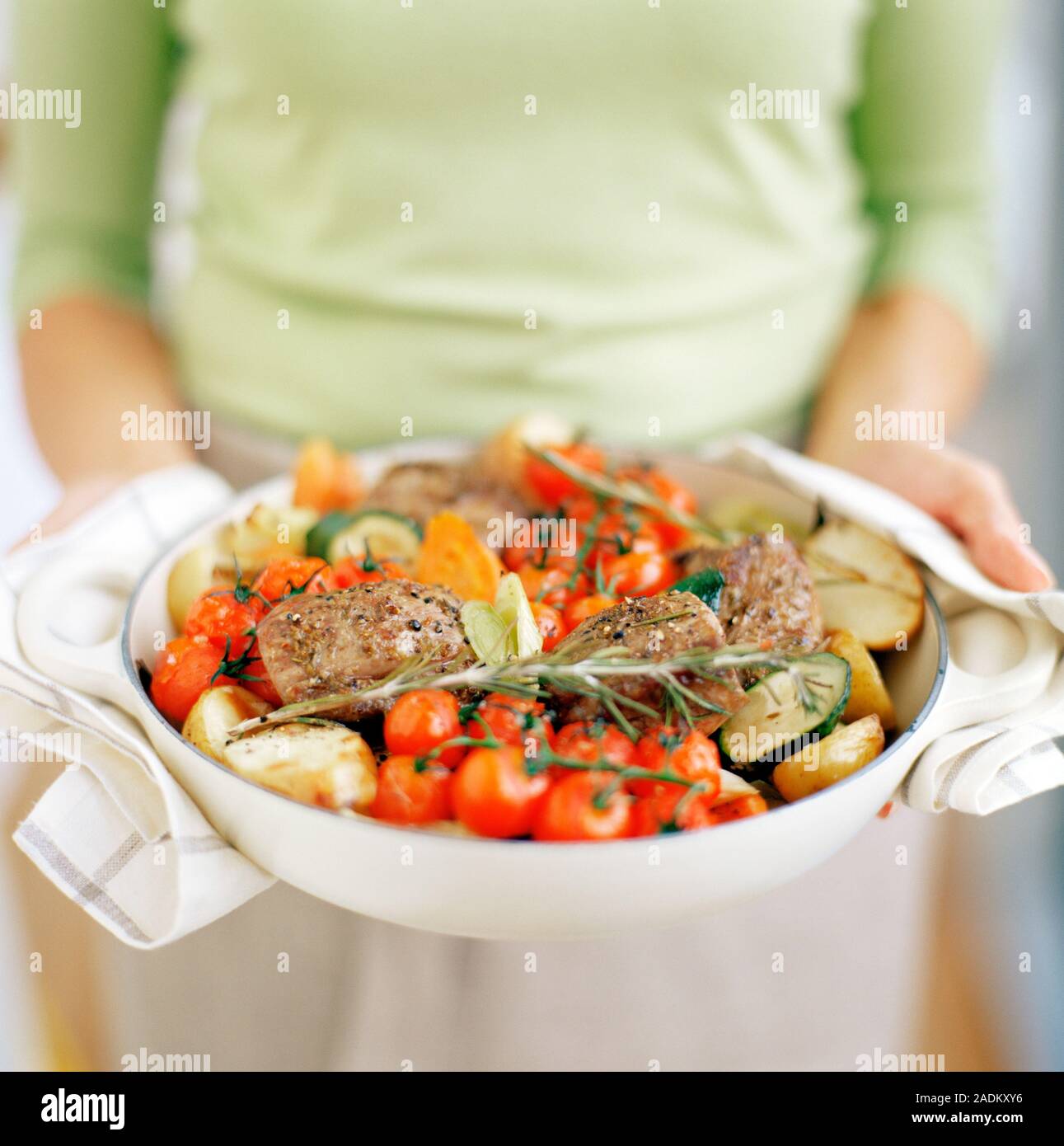Serving food. Woman carrying a dish containing a meal of seasoned meat ...