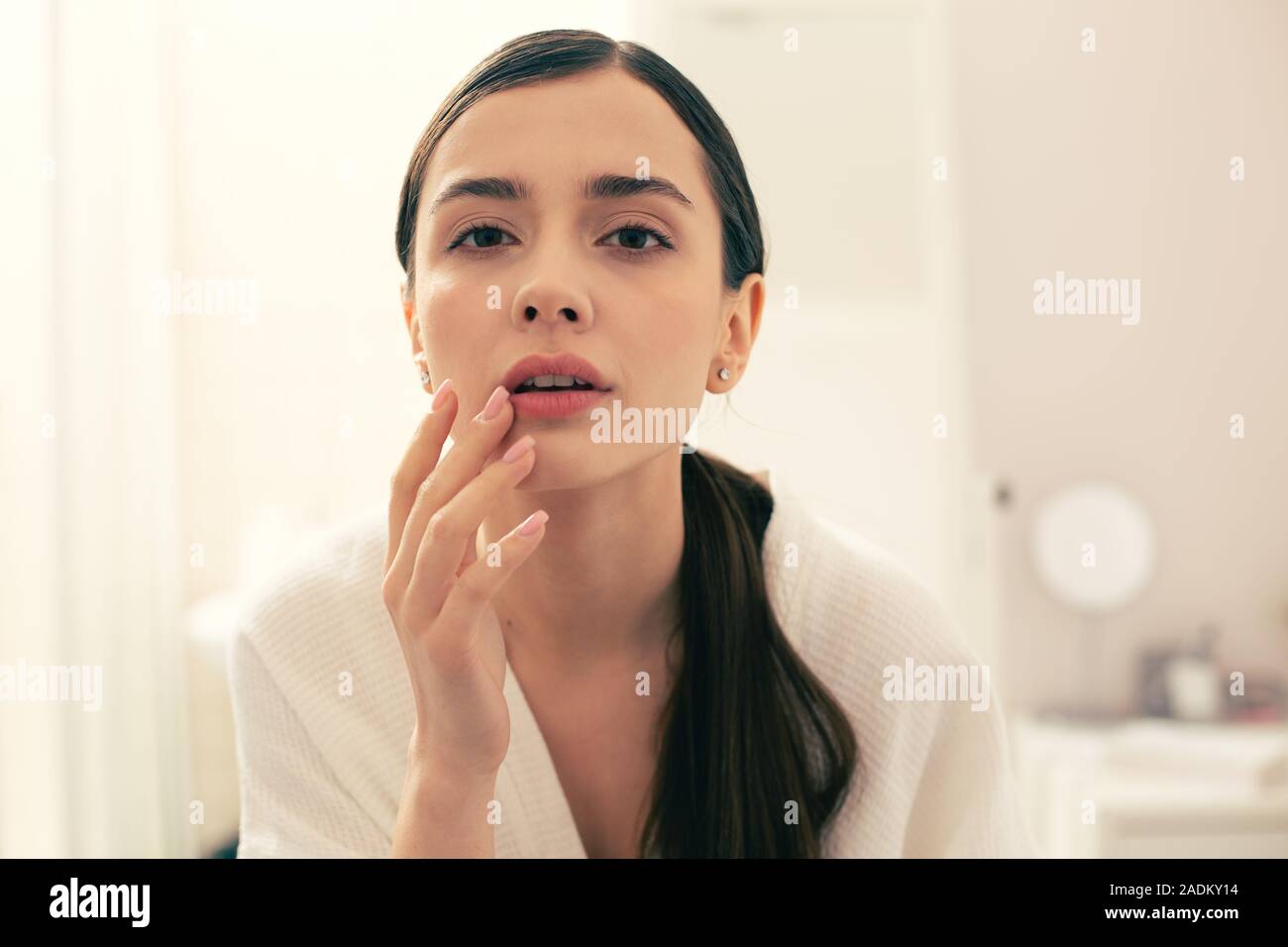Thoughtful woman touching her lips and looking away Stock Photo - Alamy