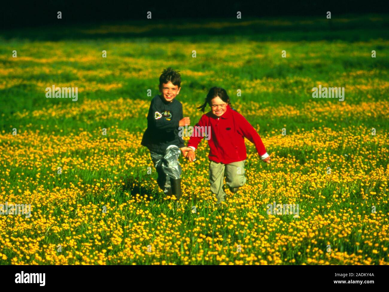 Enjoying the countryside. Two happy children running through a field of ...