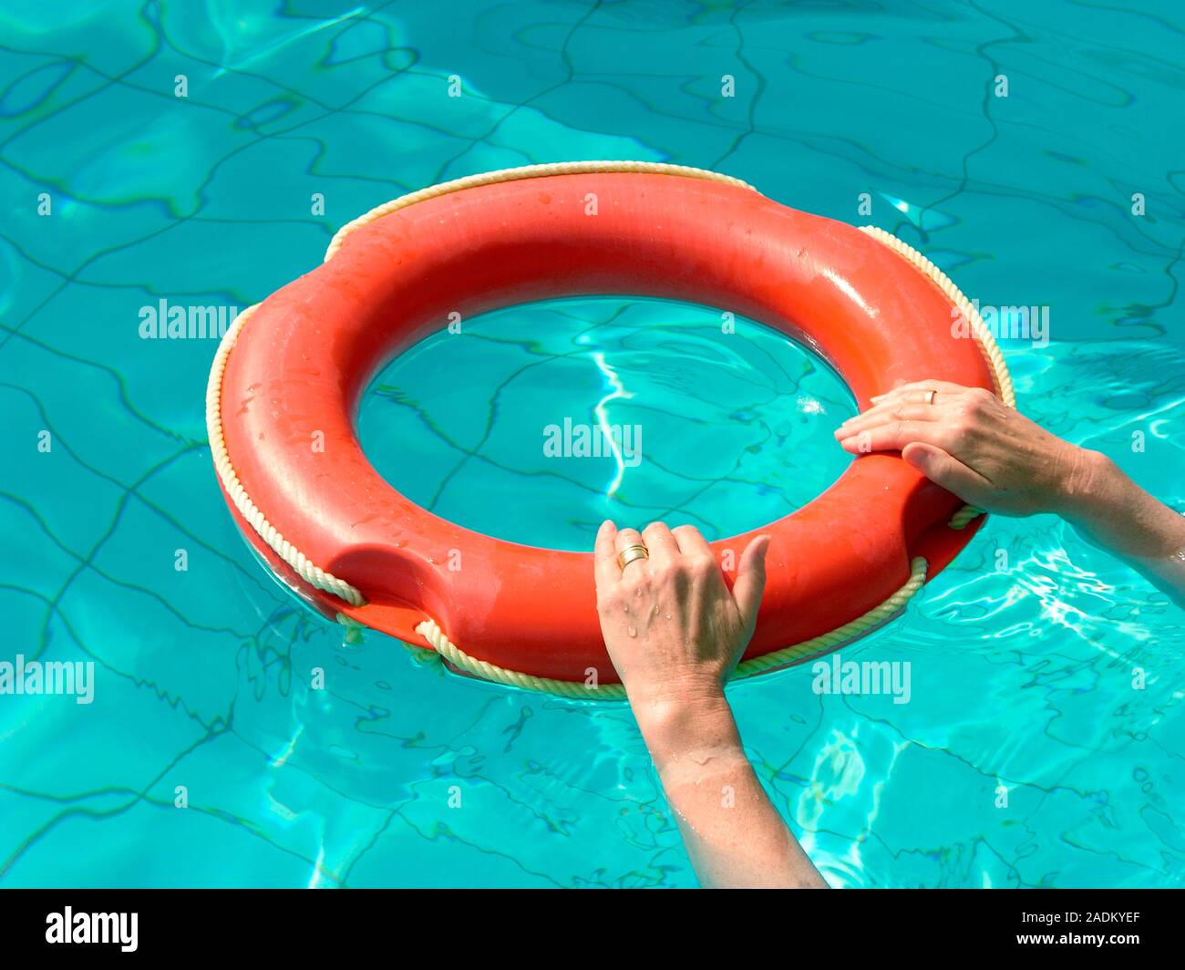 Pool side life preserver with a woman's hands holding on for safety ...