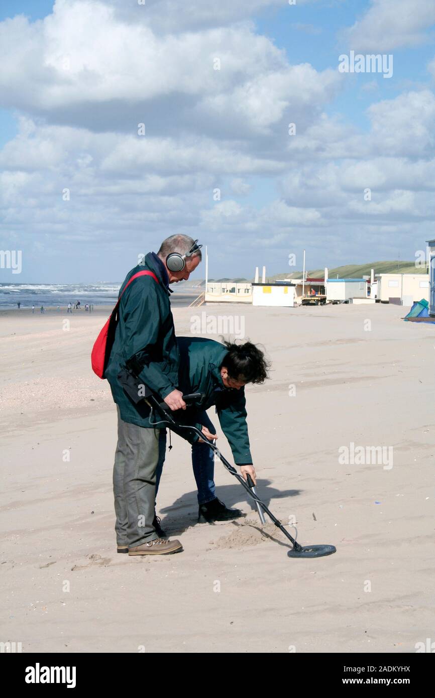 Metal detector use. People using a metal detector to hunt for buried ...