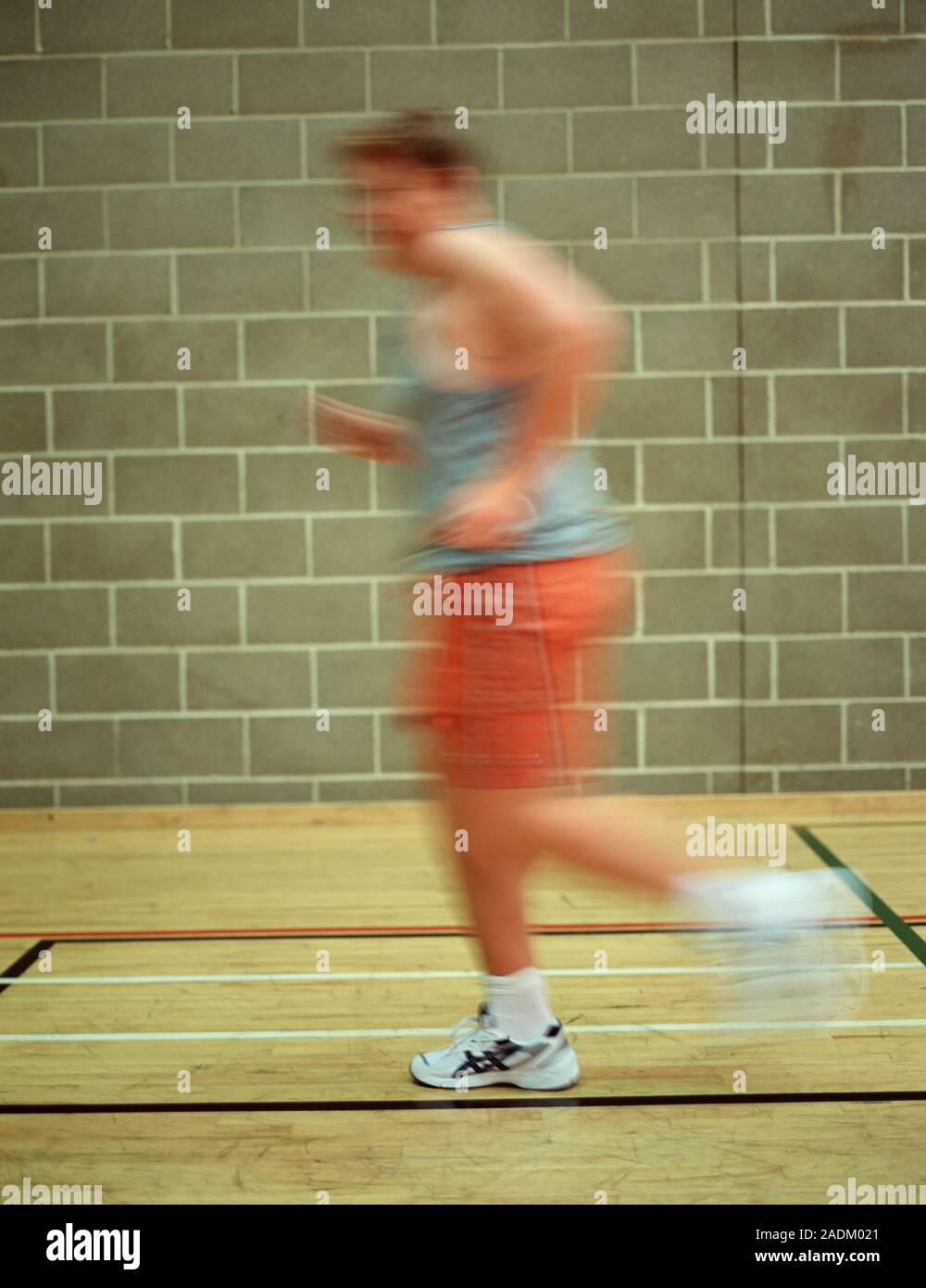 Running. Blurred image of an overweight boy running in a gymnasium ...