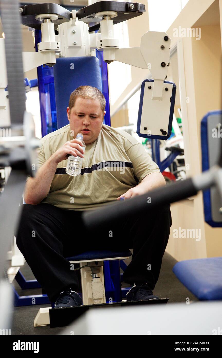 Obese man exercising. Obese man drinking from a bottle of water while ...