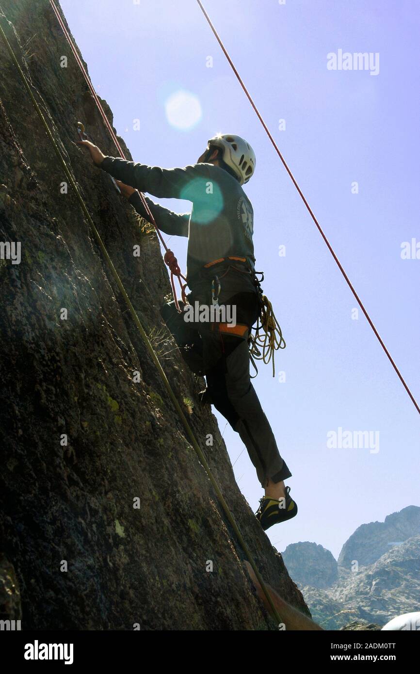 MODEL RELEASED. Rock climber climbing a steep rock face. This type of ...