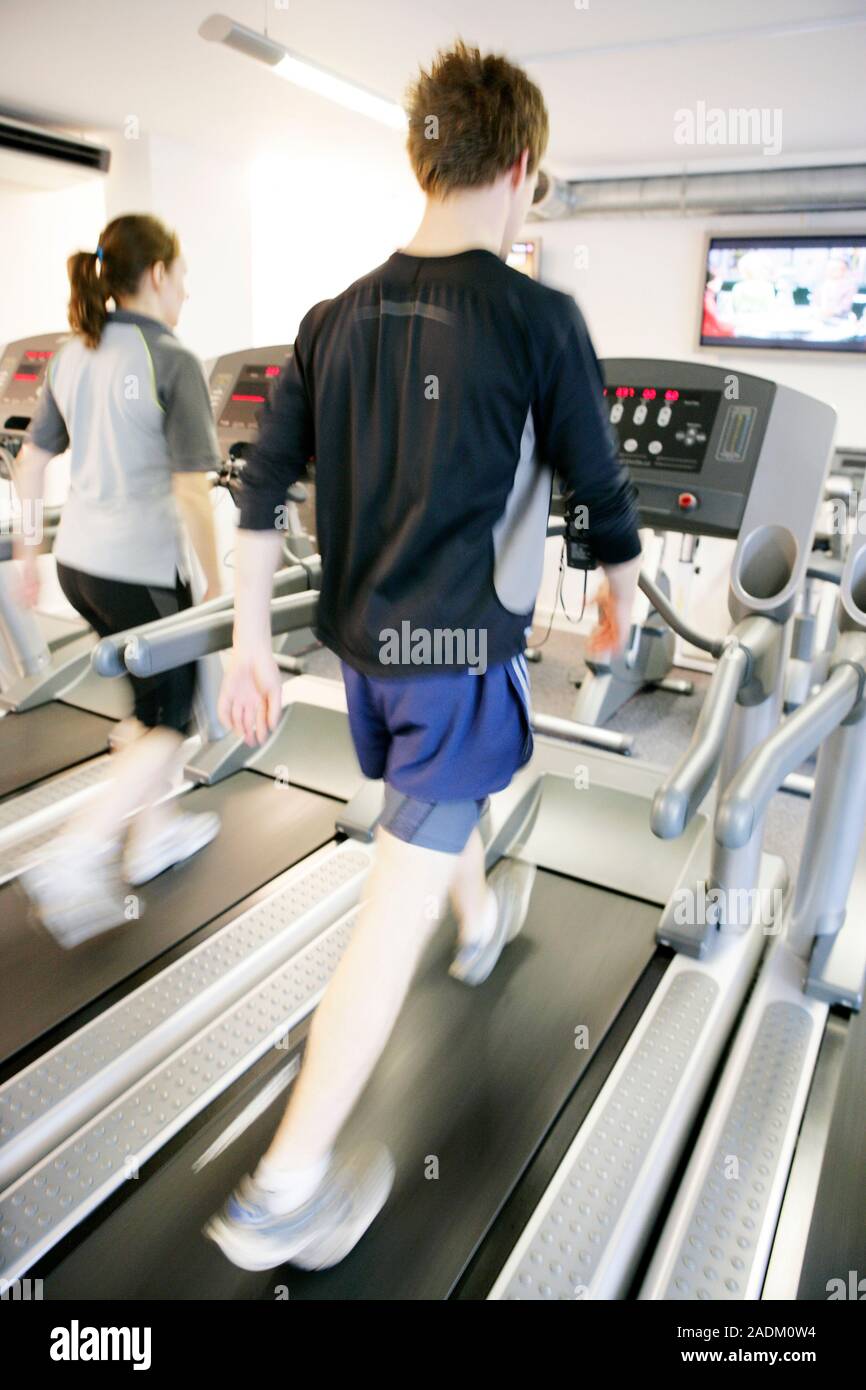MODEL RELEASED. Running machines. Man and woman exercising on running ...