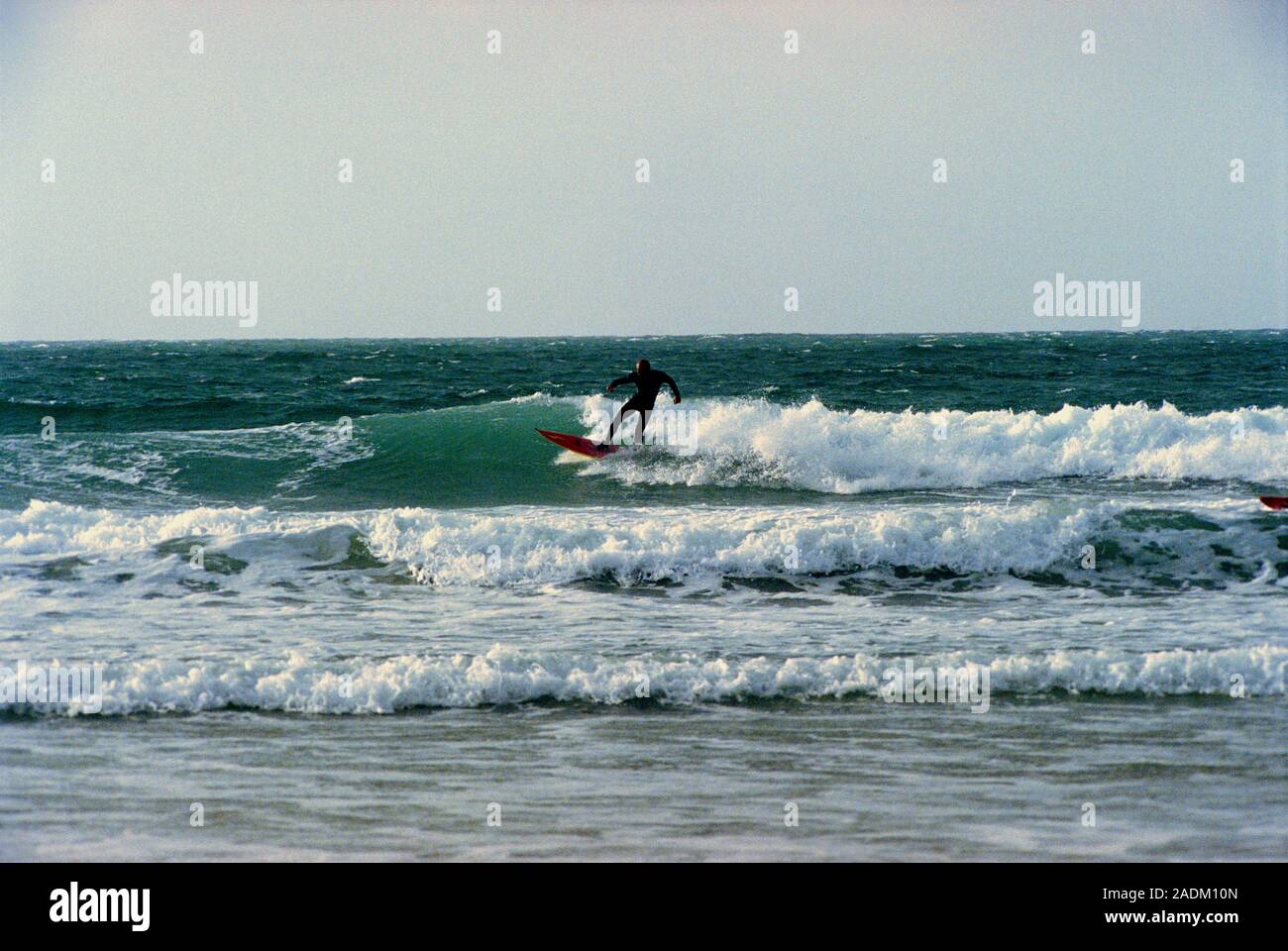 Surfer. Surfing student riding a surfboard off Fistral Beach, England ...