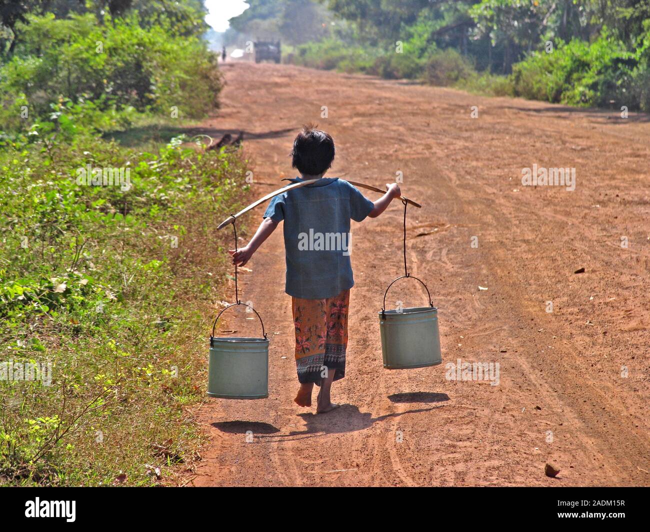 Boy carrying drinking water in buckets on his shoulders. Photographed ...