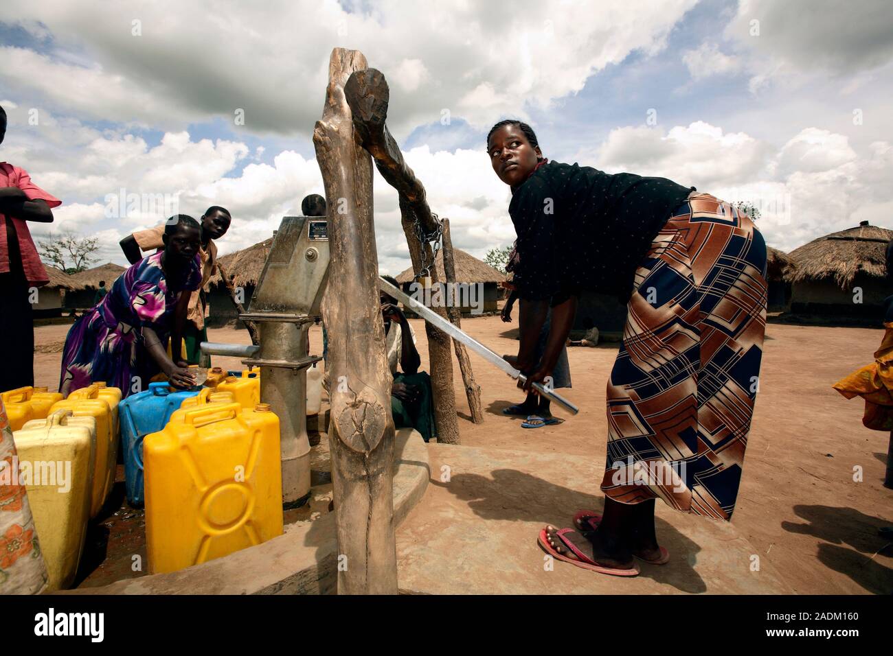 Water collection. People using a water pump to fill their water cans ...