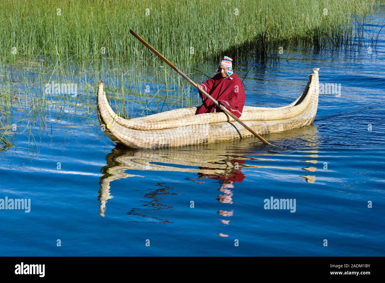 Traditional Bolivian boat. Man in traditional Bolivian dress paddling a ...