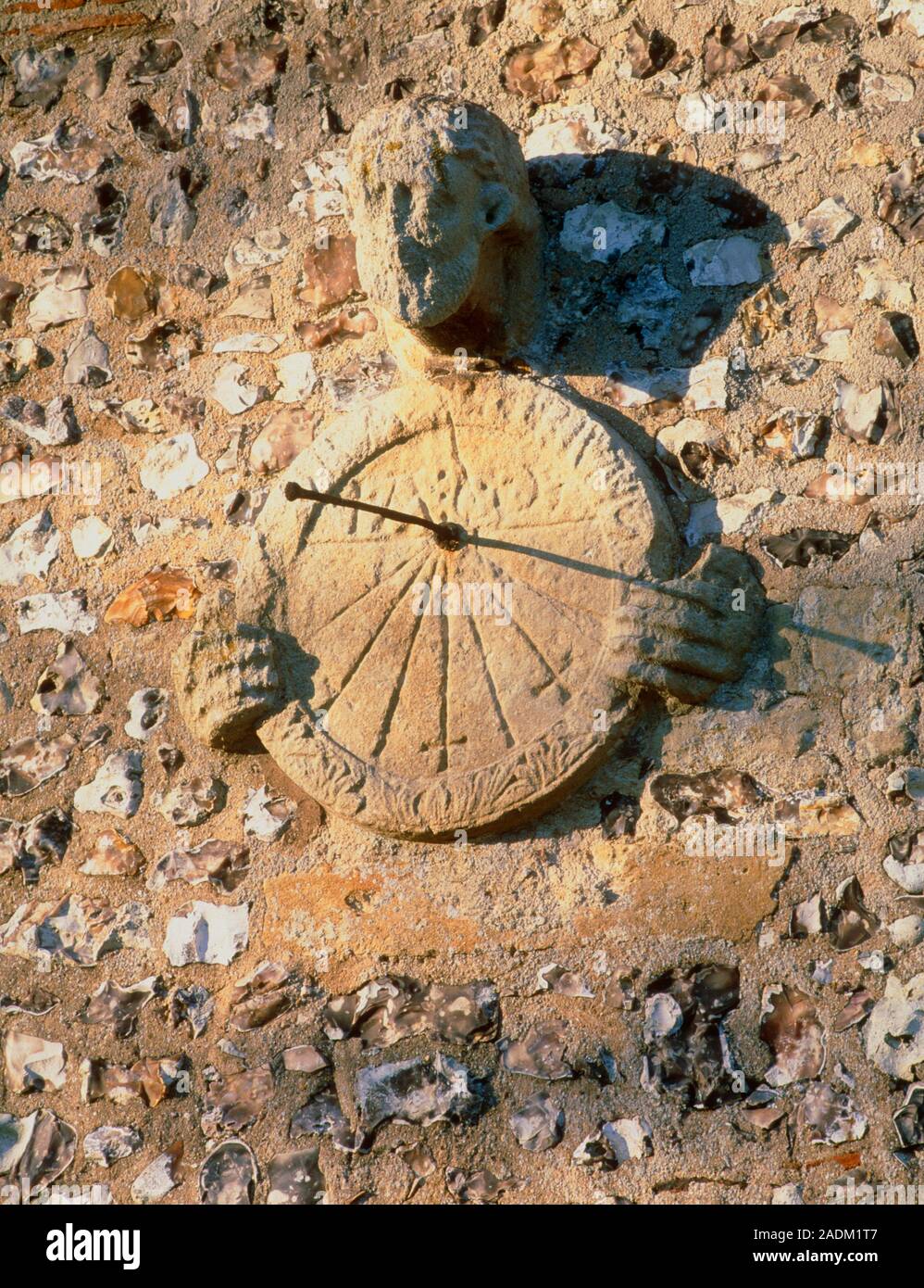 Sundial. Statue of the head and hands of a priest holding a stone ...