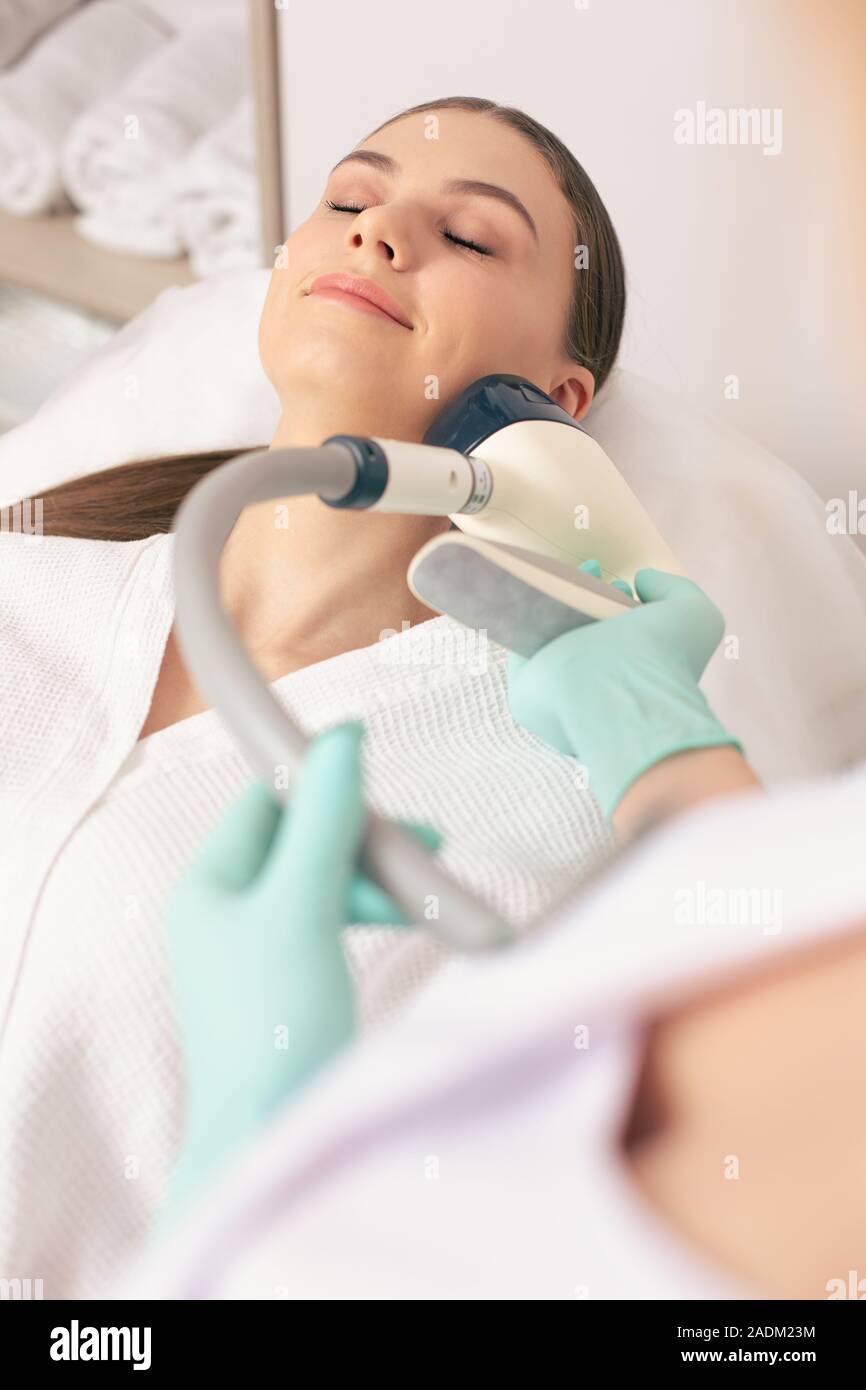 Smiling woman undergoing non-invasive body modeling procedure Stock ...