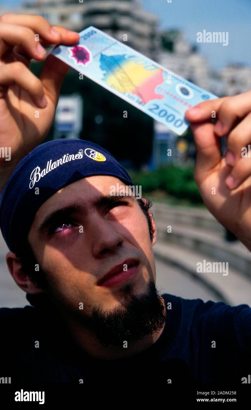Watching a solar eclipse. Man looking through a banknote to observe a ...