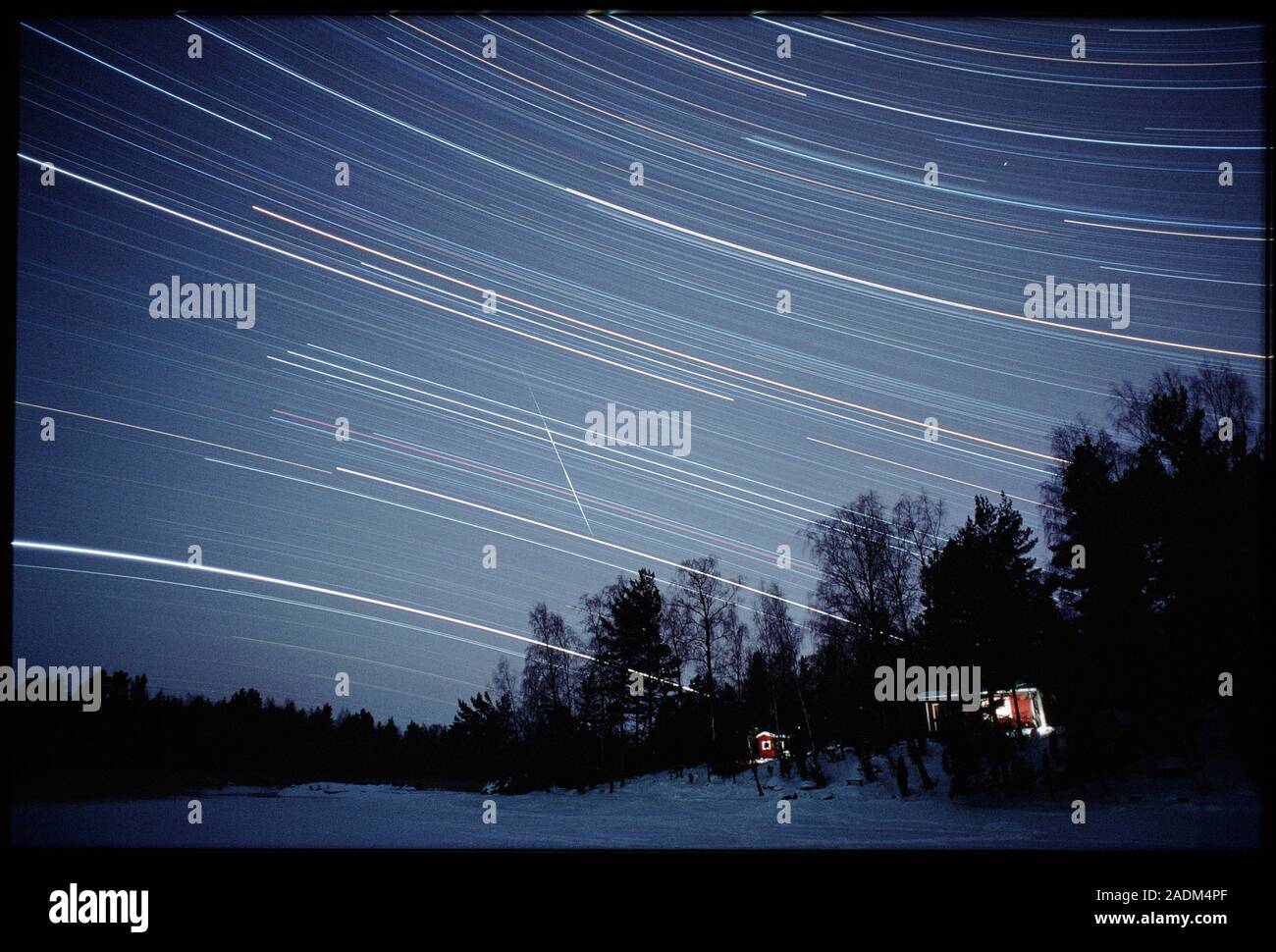 Meteor track. Time-exposure image of a night sky over trees showing a ...