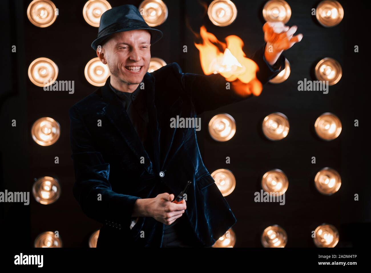 Professional magician showing trick and playing with fire. Light bulbs ...