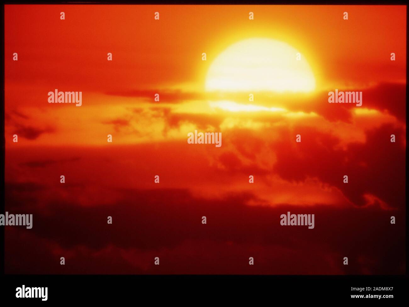 Sunset. The Sun setting behind clouds. Solar radiation seen at sunset ...