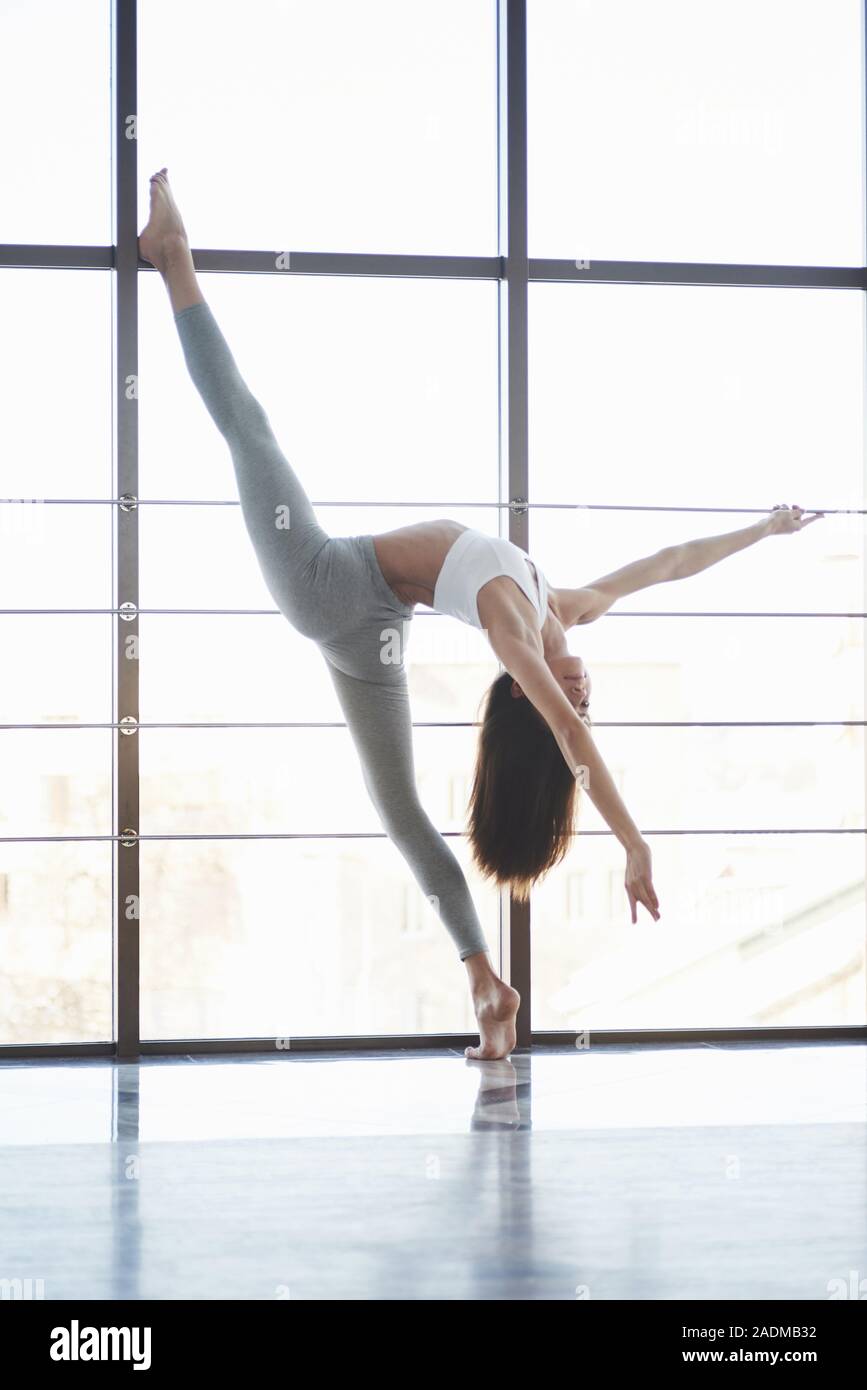 Vertical photo. Side view of girl in sportswear doing stretch exercises ...