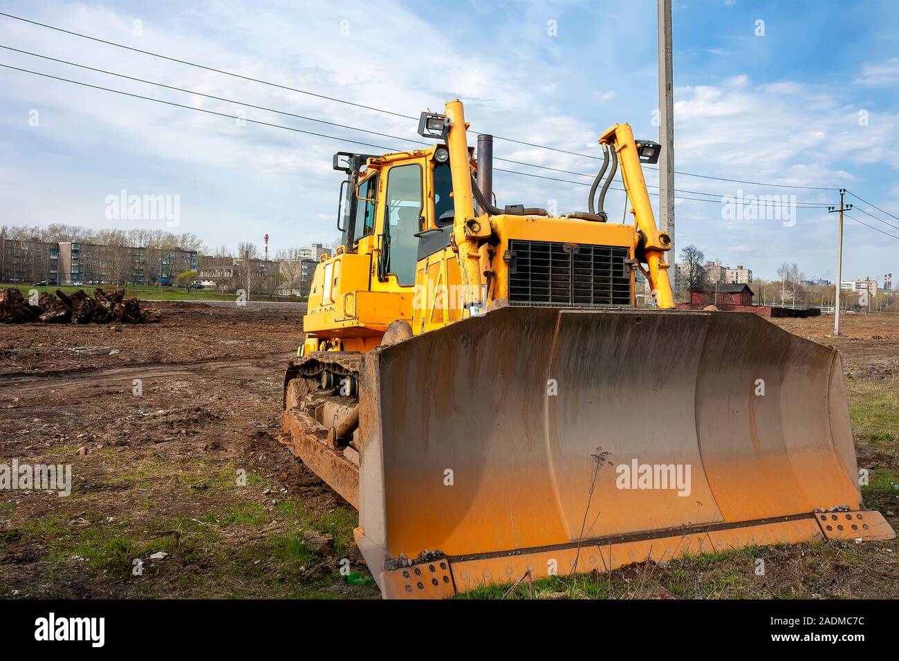 A large orange bulldozer with a blade stands at a construction site ...