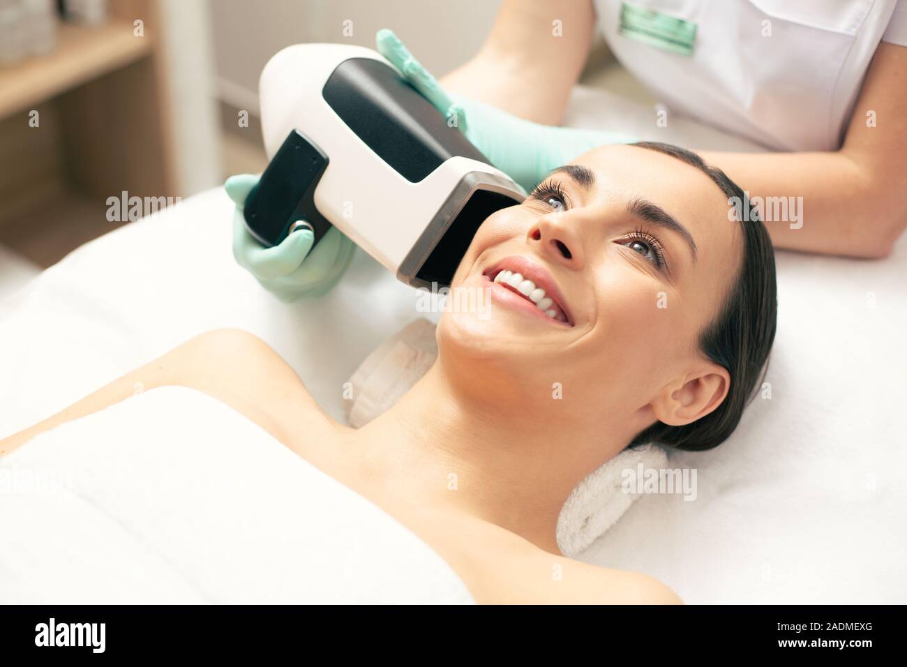 Emotional woman smiling while undergoing skin analysis procedure Stock ...