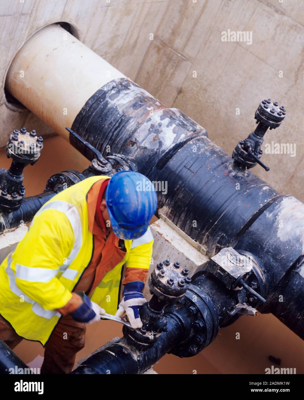 Repairing gas pipeline. Worker using a spanner to repair an underground ...