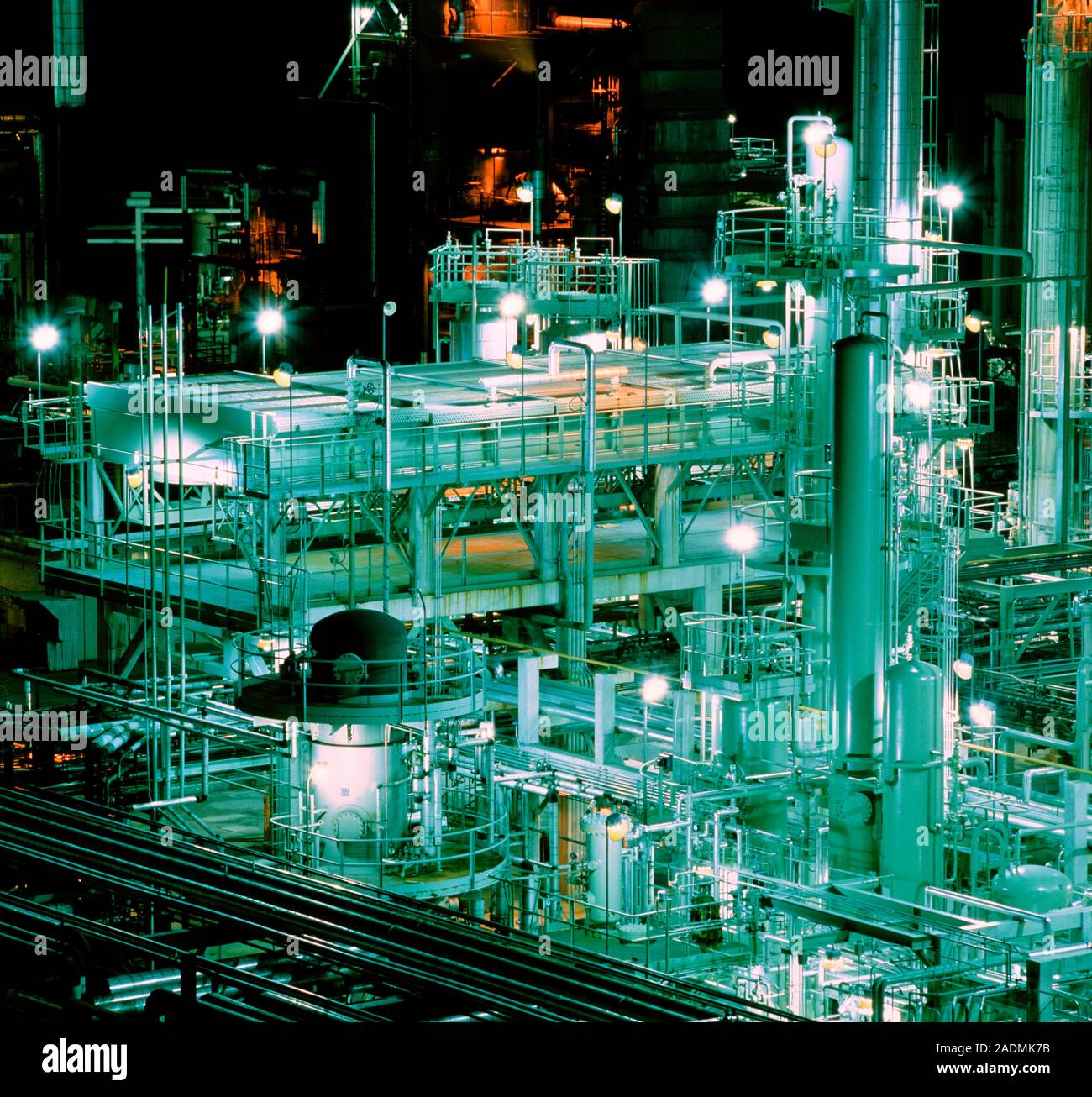 Oil refinery at night. At the refinery, crude oil is heated and passed ...