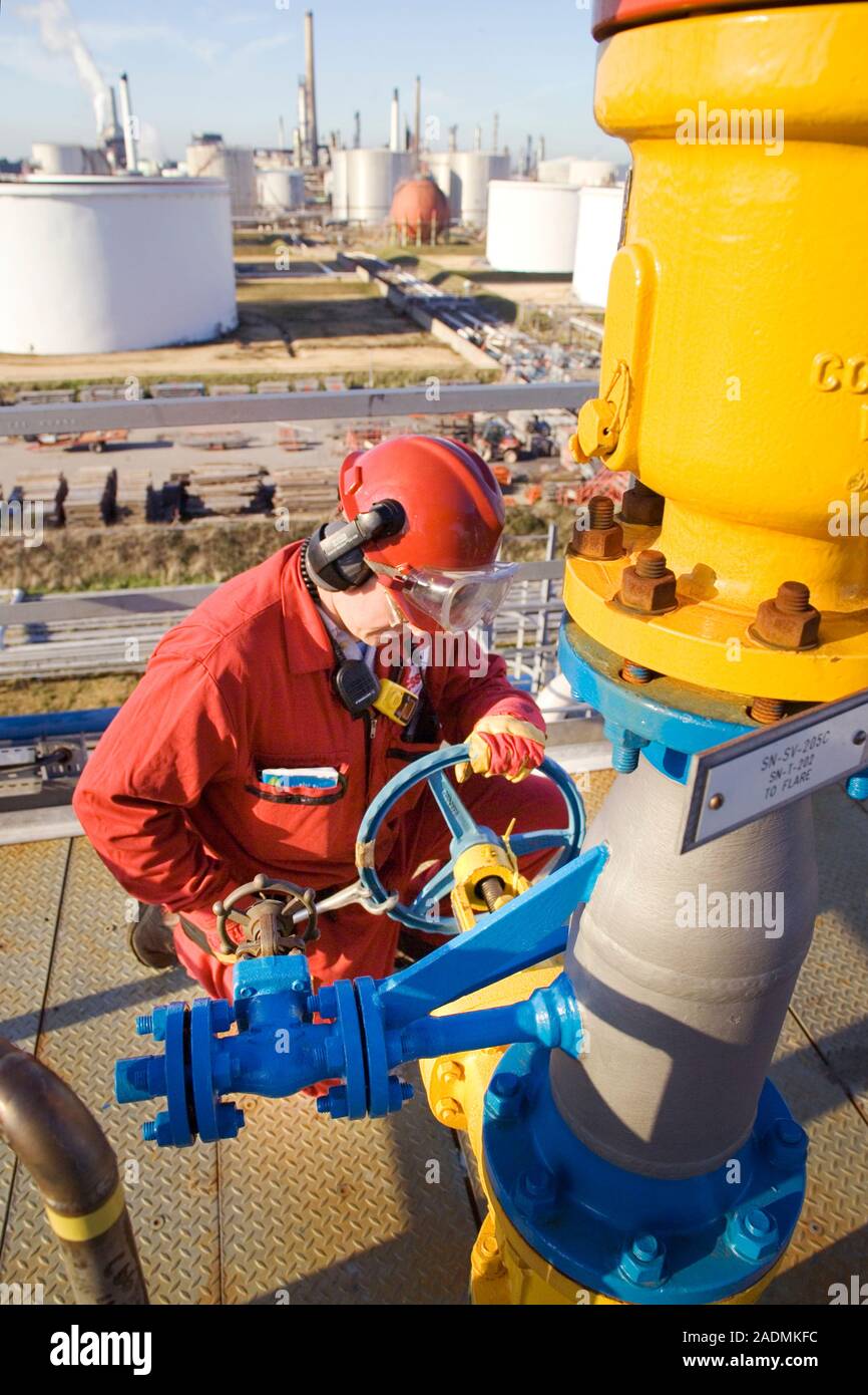 Oil refinery worker checking a safety valve on top of a tower in the ...