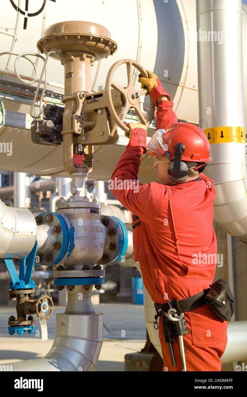 Oil refinery worker checking a safety valve on a heat exchanger unit in ...
