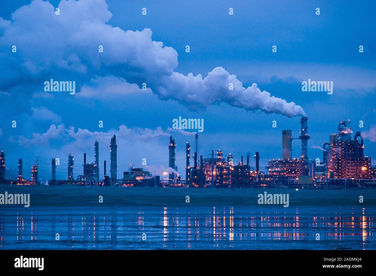 Oil refinery at dusk. A tailings pond, for the disposal of waste ...