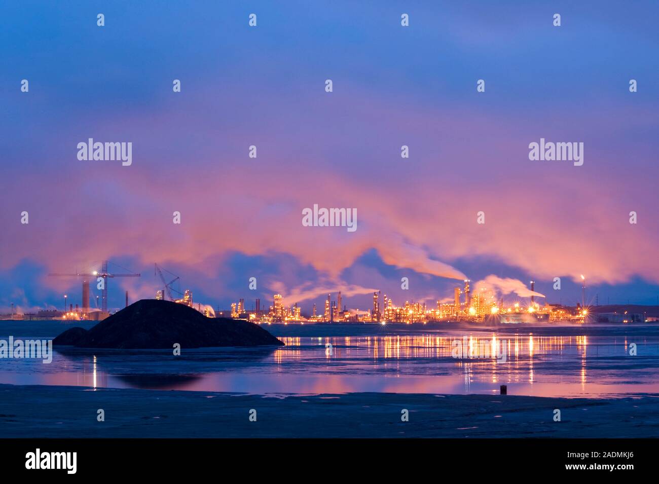 Oil refinery at night. A tailings pond, for the disposal of waste ...