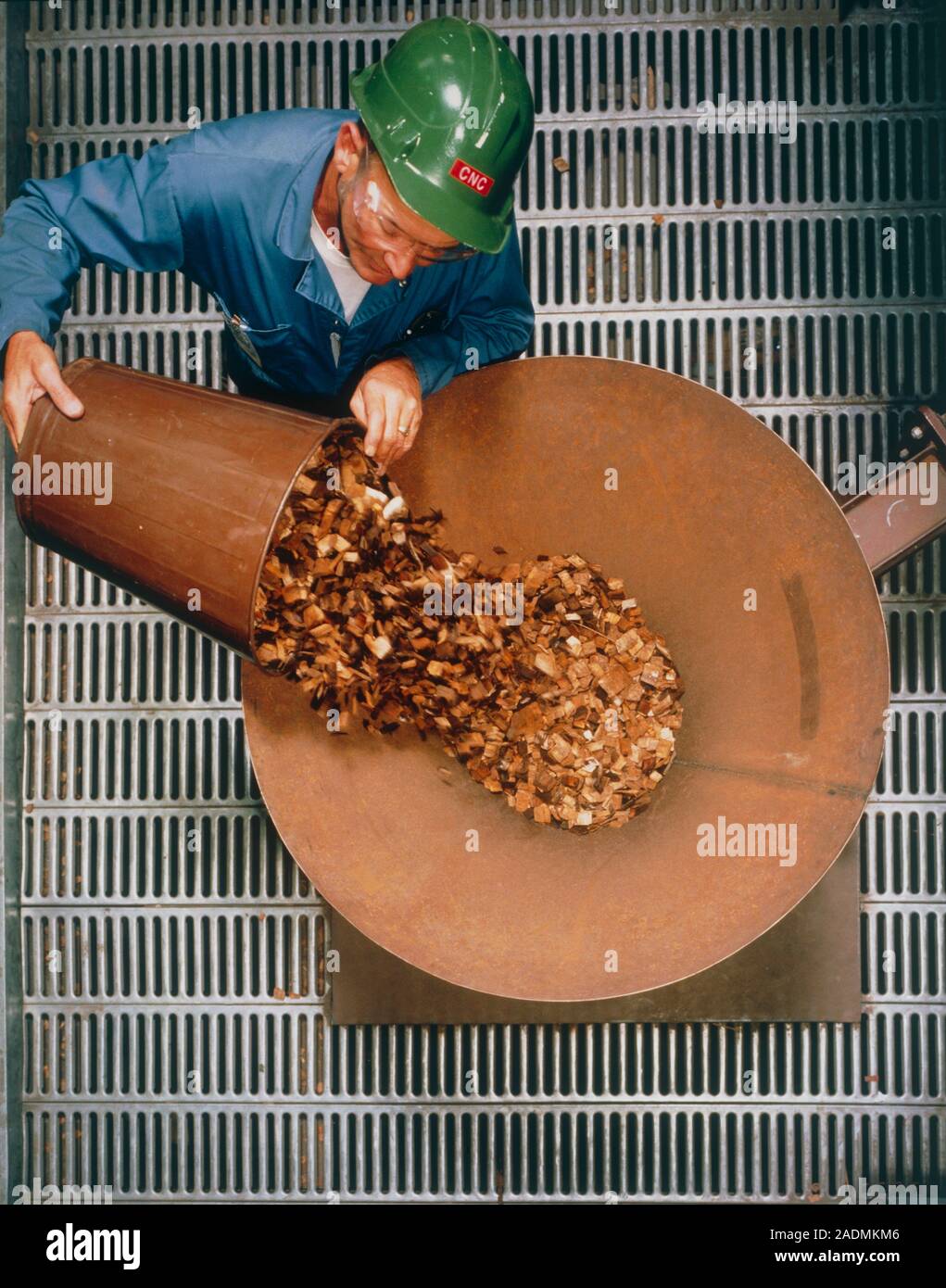 A worker loads woodchips into the hopper of an experimental reactor ...