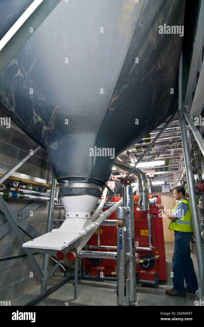 MODEL RELEASED. Hopper storing biomass pellets. Technician checking the ...