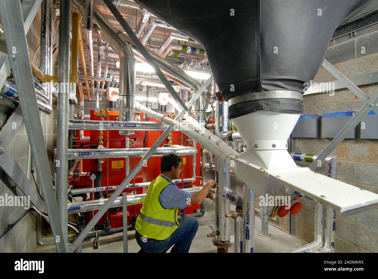 MODEL RELEASED. Hopper storing biomass pellets. Technician checking the ...