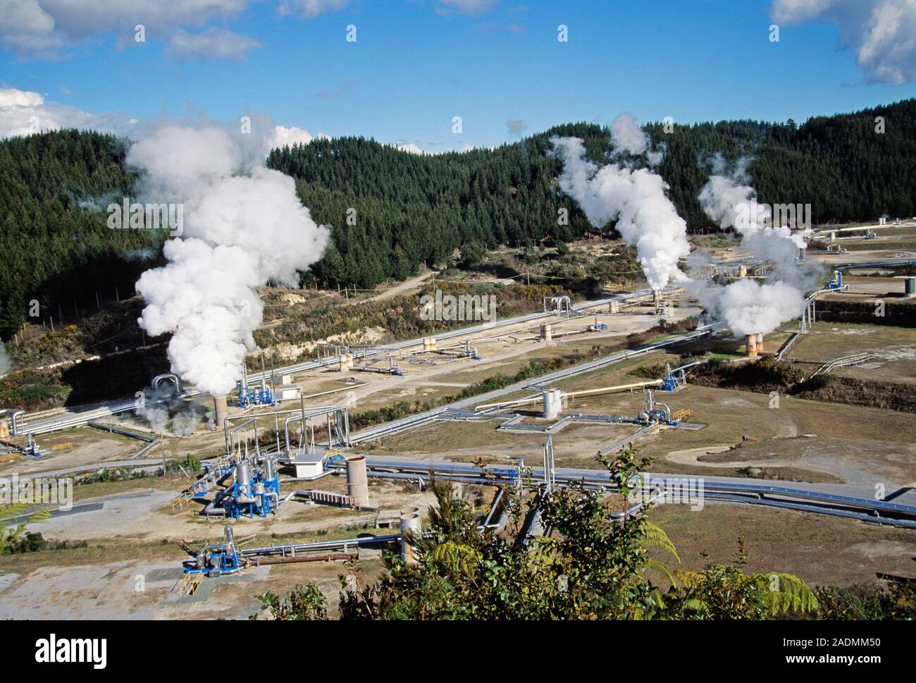 Geothermal power station. Steam rises from a network of insulated pipes ...