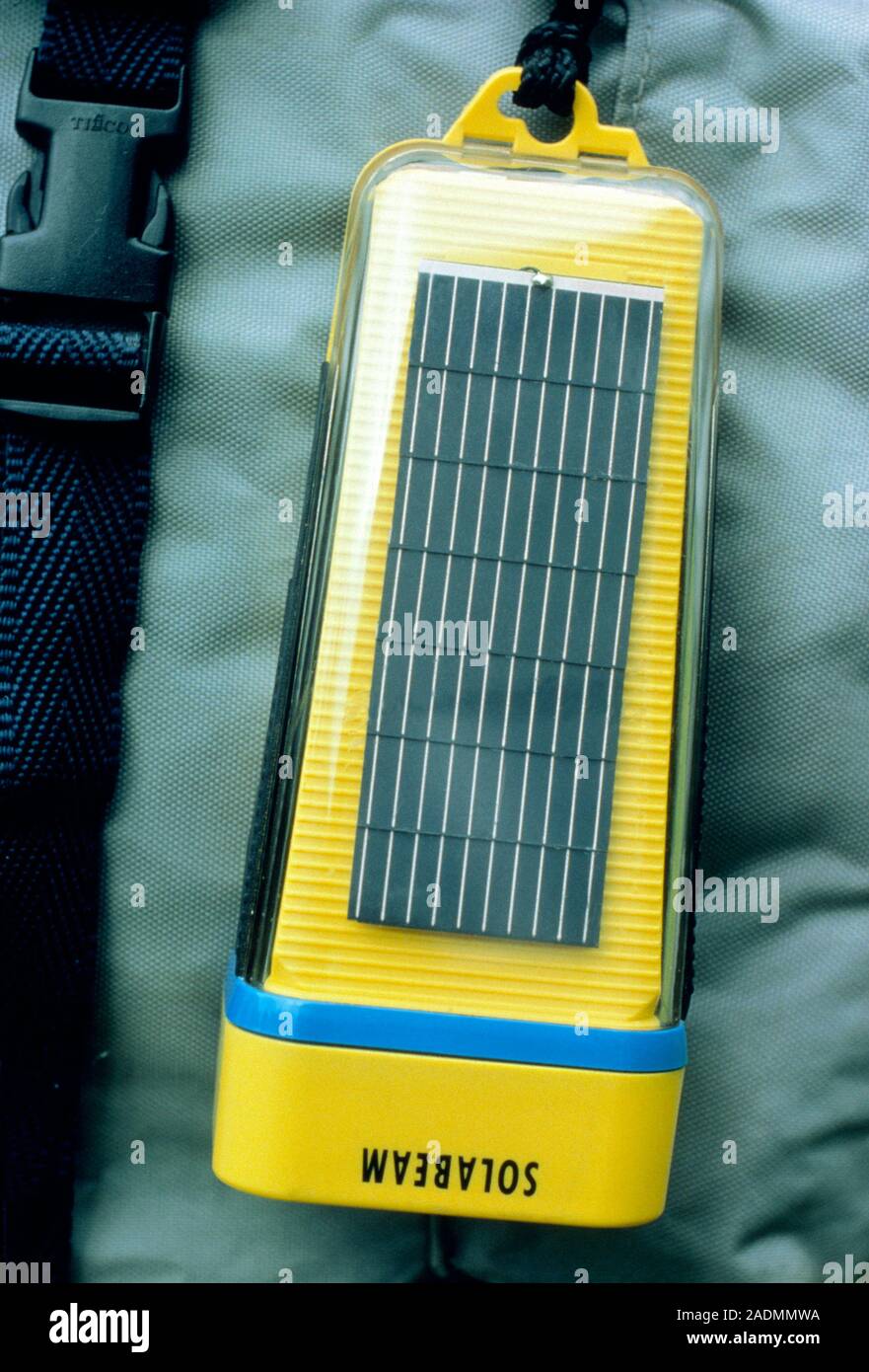 Solar powered torch. Solar powered torch (yellow) on a backpack (grey ...