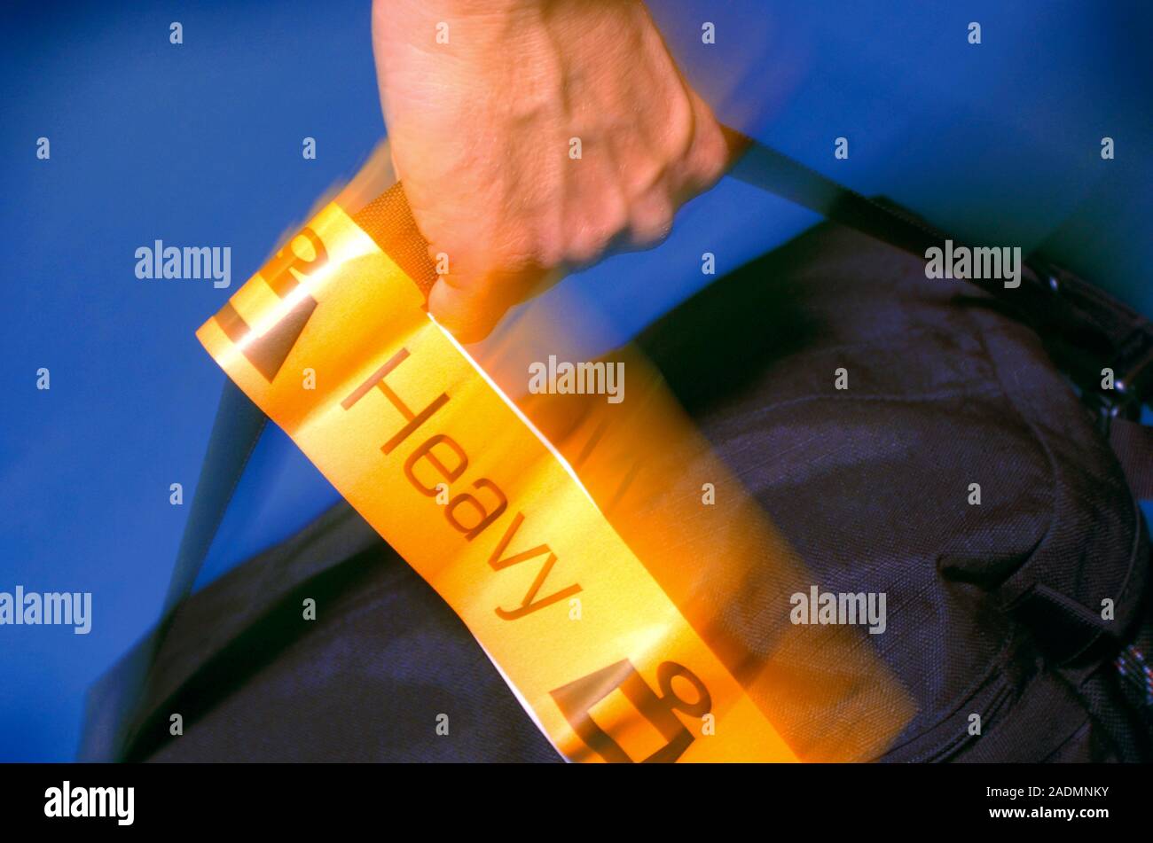 MODEL RELEASED. Heavy item warning label on luggage being carried by ...