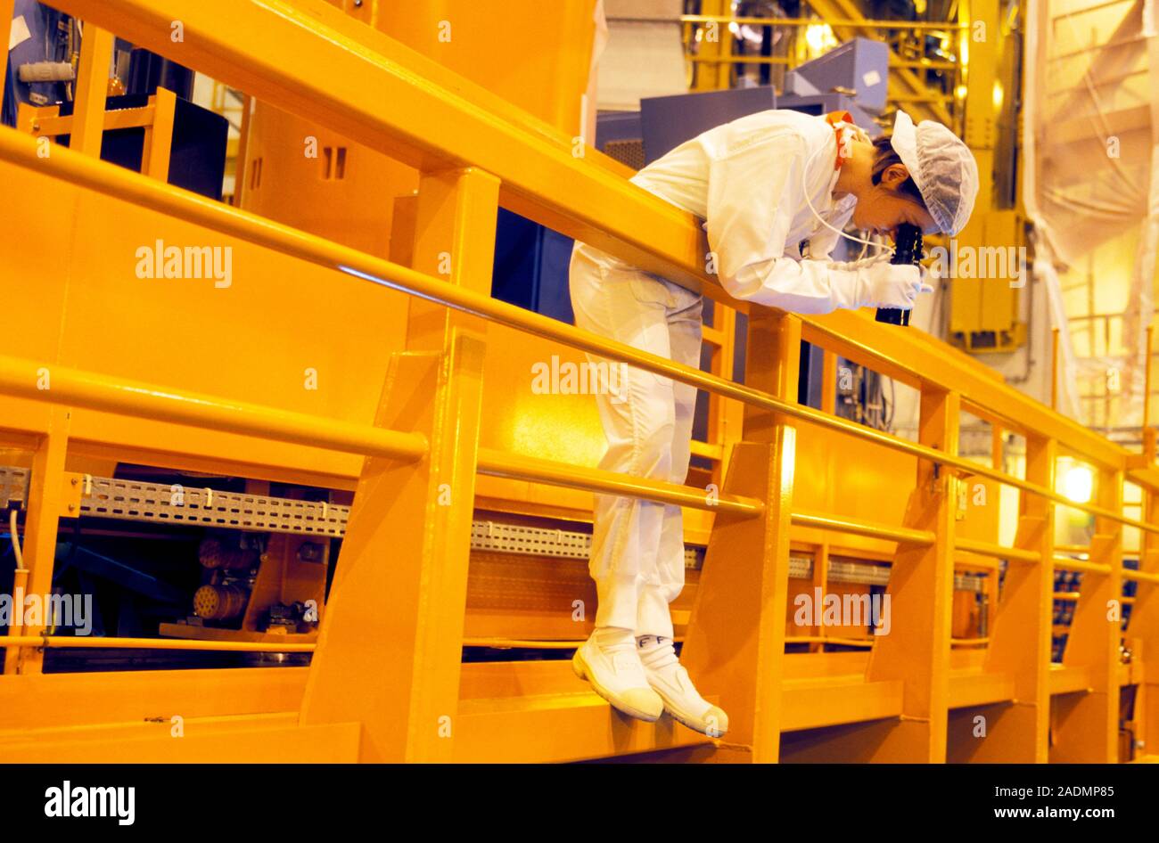 Nuclear reactor fuel loading. Worker using binoculars to check the ...