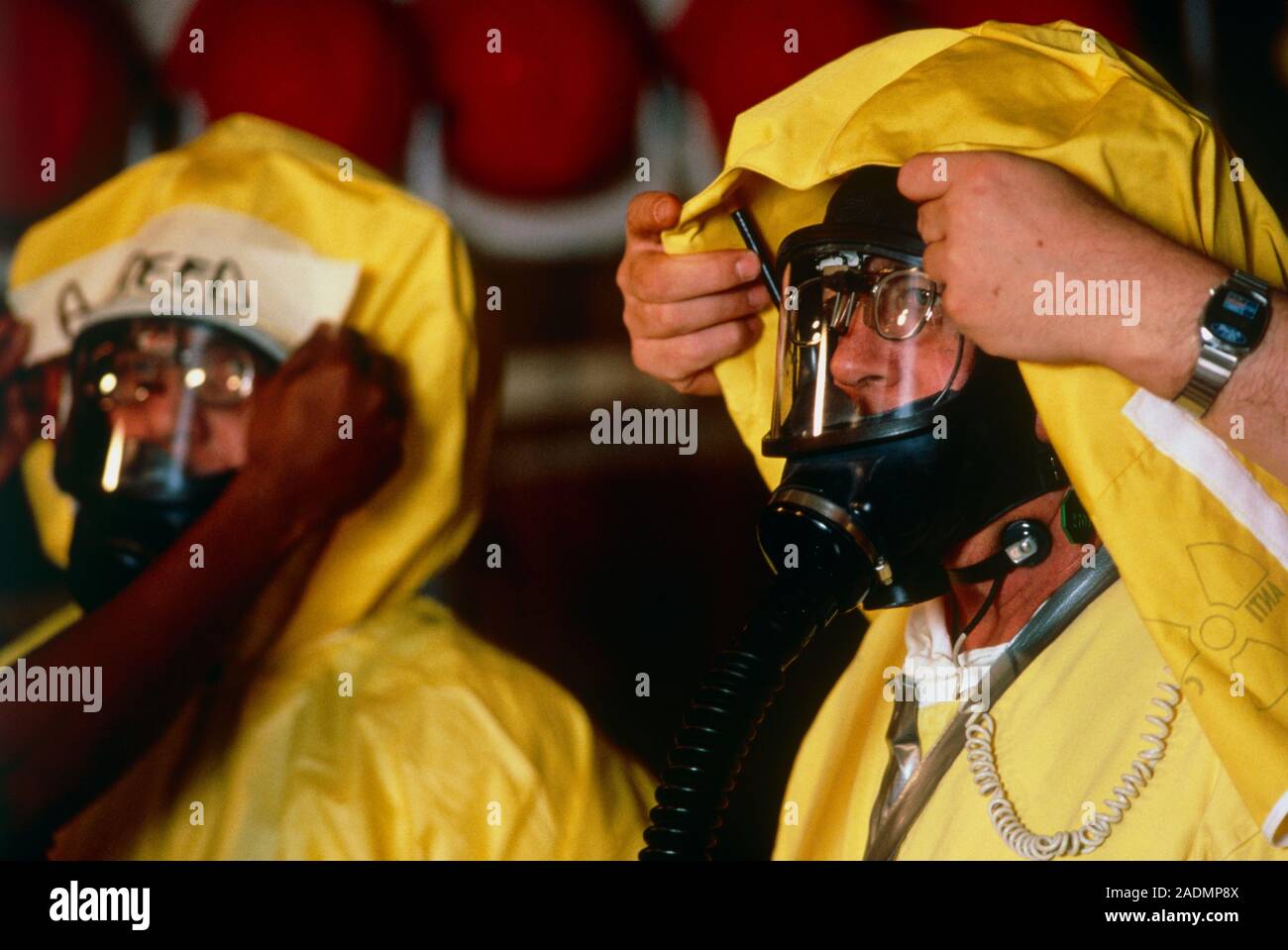 Two workers being fitted with protective clothing and oxygen masks ...