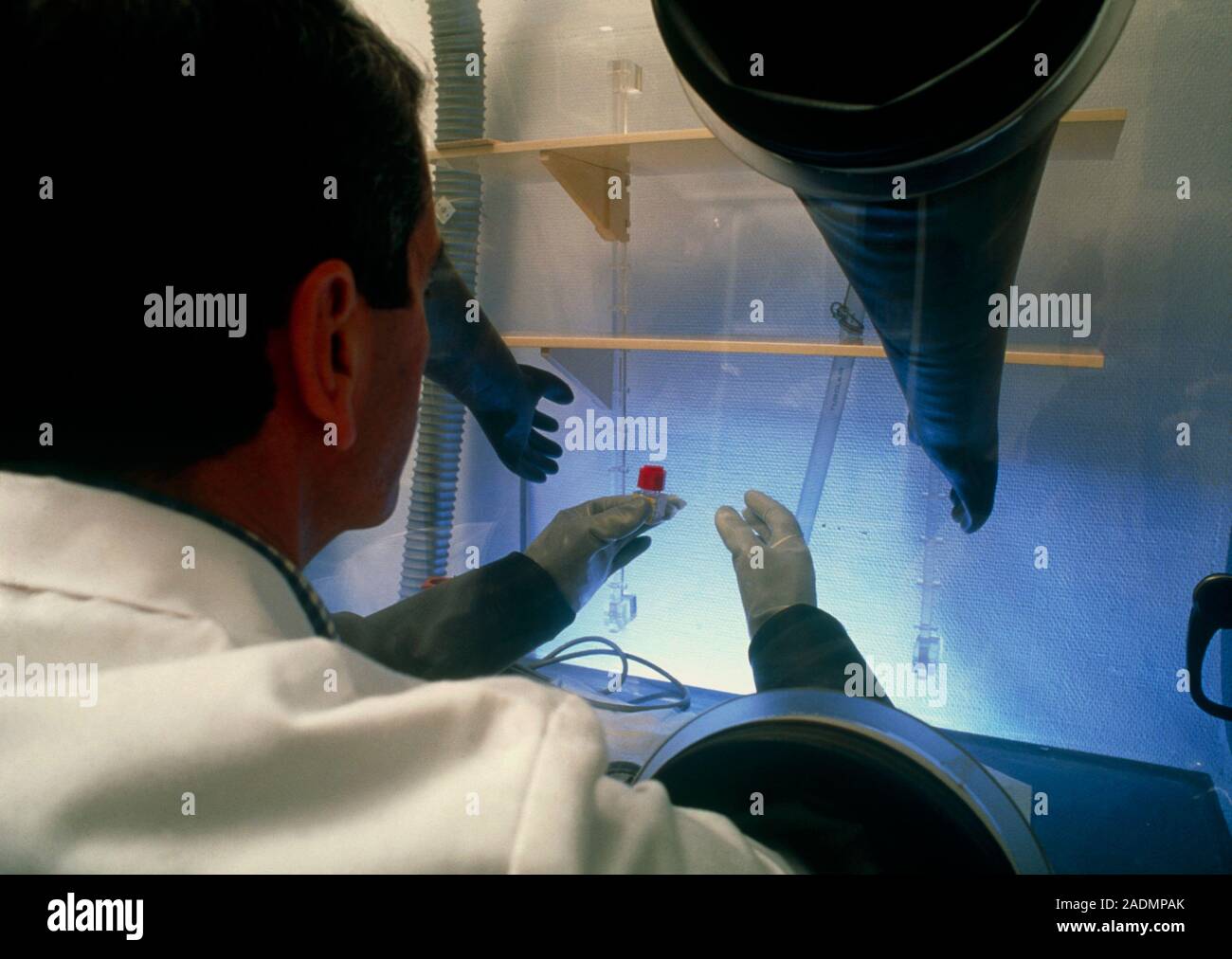 Radioactive research. Male technician handling a bottle of radioactive ...