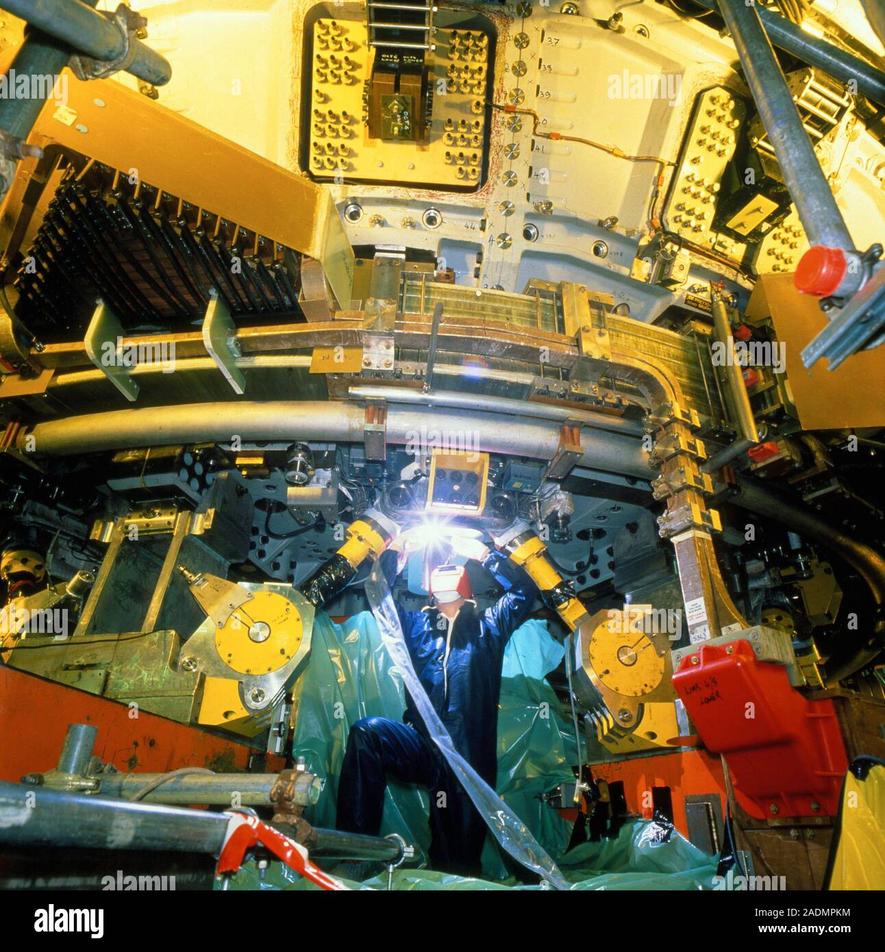 Nuclear fusion reactor. An engineer welds compon- ents on the ...