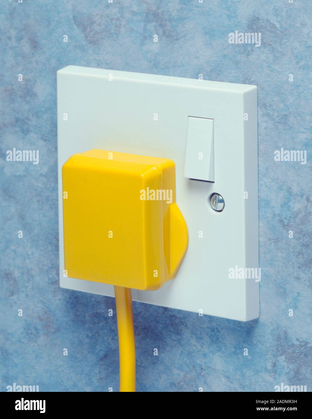 Three-pin plug in an electrical socket. Pushing the socket switch ...