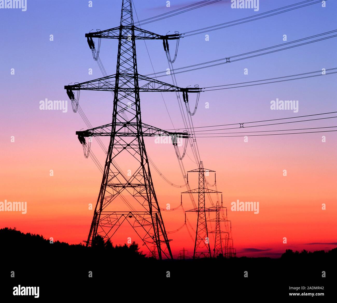 Electricity pylons at sunset. These pylons carry the high tension (high ...
